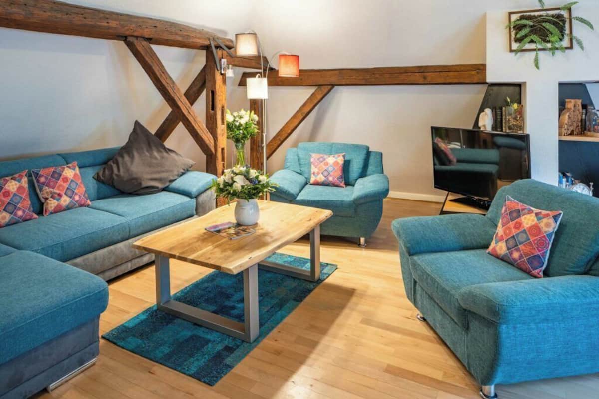 Uma sala de estar acolhedora com sofás azuis, uma mesa de centro de madeira e uma TV.