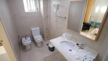 Casa de banho com duas sanitas, uma pia, um chuveiro e um espelho.