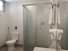 Casa de banho com sanita, cabine de duche e secador de cabelo.