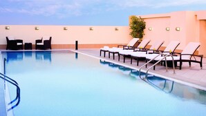Piscina com espreguiçadeiras e parede iluminada.