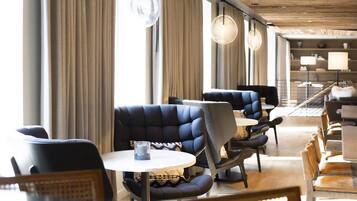 Um hall de hotel moderno com assentos confortáveis, janelas amplas e iluminação suave.