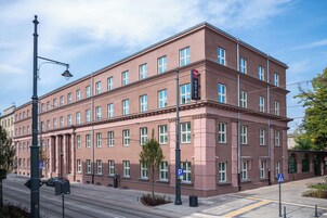 Um hotel grande, com vários andares, de estilo arquitetônico clássico, com uma entrada destacada e vista clara da rua.