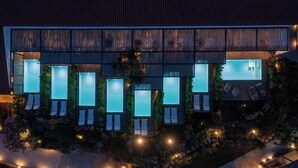 Um edifício moderno com vários quartos, cada um com parede de vidro e varanda.