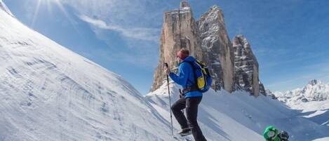 Paisagem de montanhas nevadas com um alpinista vestindo jaqueta azul e verde.