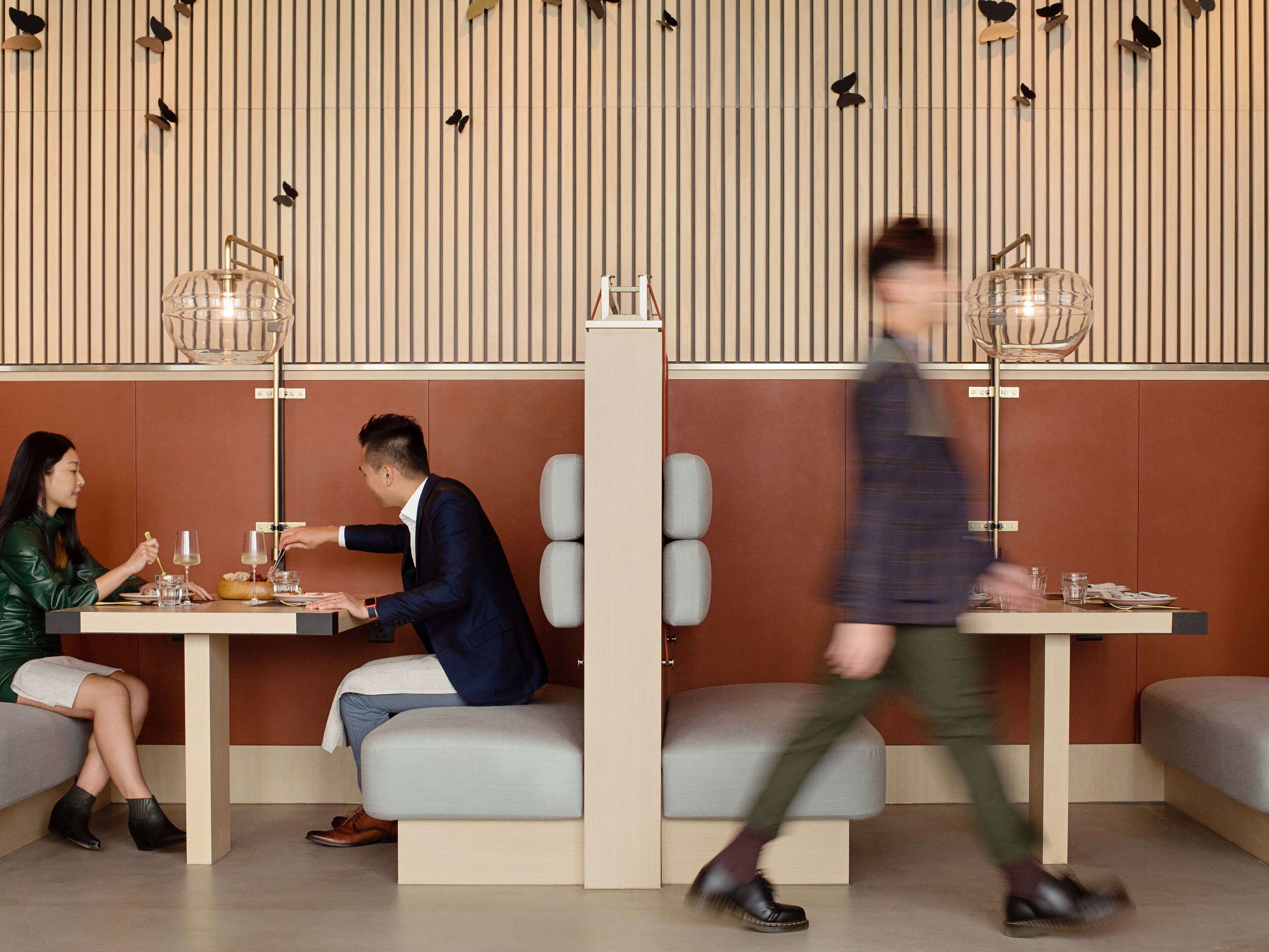 Restaurante moderno com design minimalista, apresentando uma área de estar central com bancos acolchoados e teto alto com detalhes decorativos.