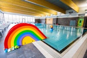 Piscina com uma estrutura colorida em tons de arco-íris, água cristalina e teto de madeira.
