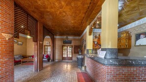 Um hall de entrada com piso estampado, paredes de tijolo e teto de madeira com detalhes elaborados.