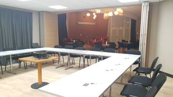 Uma sala de conferência com uma mesa comprida, cadeiras pretas e um banco de madeira.