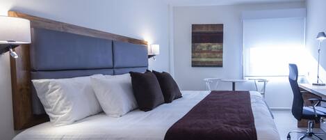 Quarto de hotel moderno com uma cama grande, uma escrivaninha e uma cadeira.
