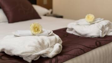 Quarto de hotel com cama, almofadas e toalhas, cada um decorado com uma rosa.
