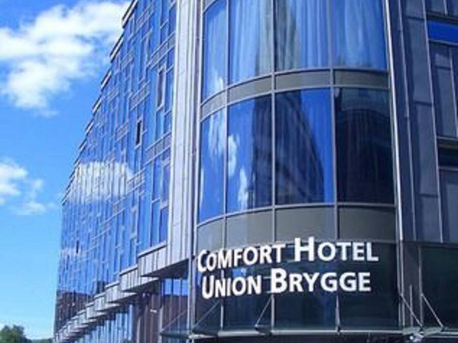 Um edifício de hotel moderno com fachada de vidro e a identificação do Comfort Hotel Union Brygge.