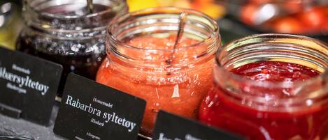Exposição de várias geleias com etiquetas indicando sabores como 'Rabarbra syltetoy' e 'Jordbærsyltetoy'.