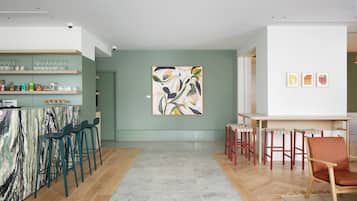 Uma cozinha moderna com bancadas de mármore, banquetas de bar e um grande quadro abstrato na parede.