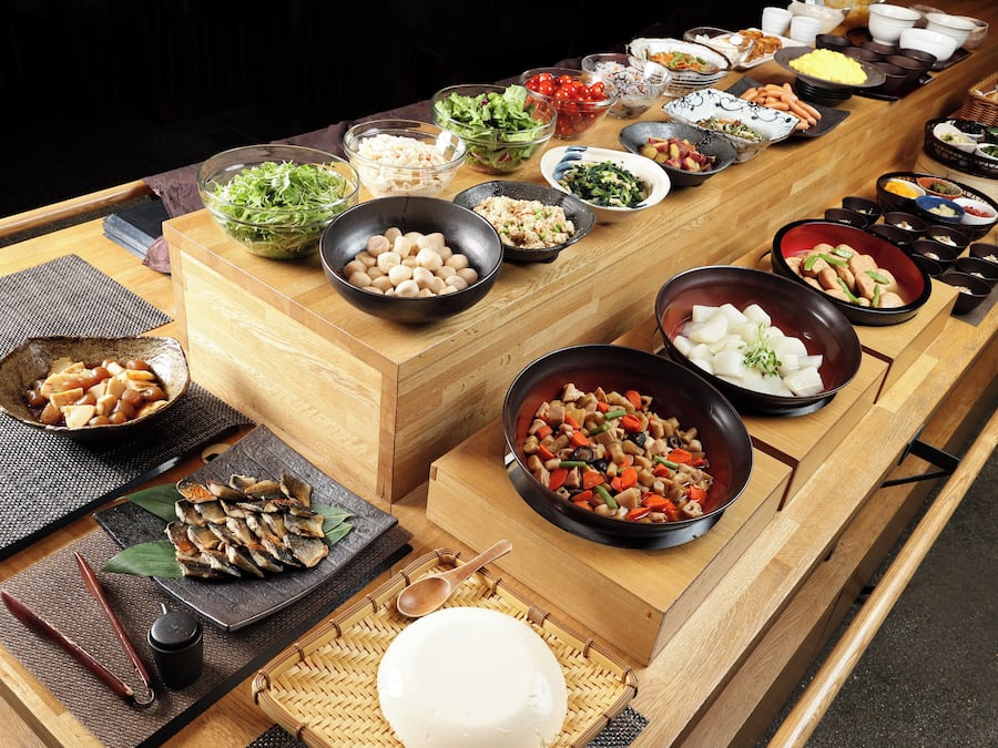 Uma mesa de buffet com diversos pratos e recipientes com comida.