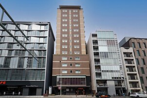 Um edifício com vários andares, com uma combinação de estabelecimentos comerciais e unidades residenciais, incluindo um hotel visível chamado Richmond Hotel Premier.