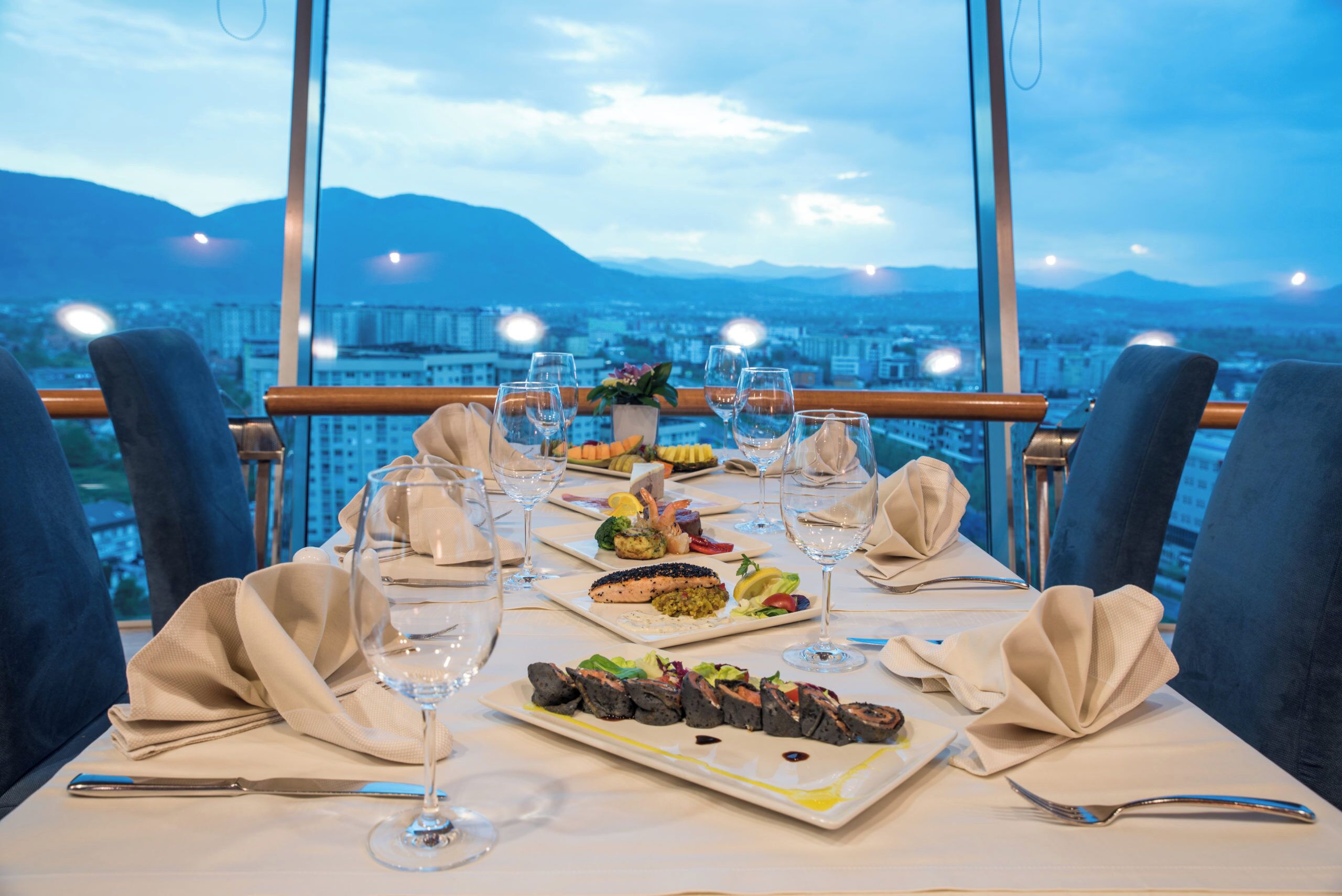 Mesa posta para o jantar com vista para a paisagem urbana, incluindo montanhas e edifícios.
