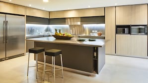 Uma cozinha moderna com ilha central, eletrodomésticos de aço inoxidável e armários de madeira.