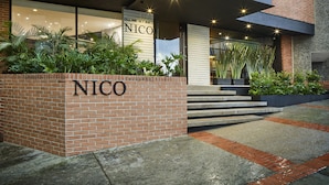 Um edifício moderno com fachada de tijolos, janelas amplas e uma placa com o nome 'NICO'.