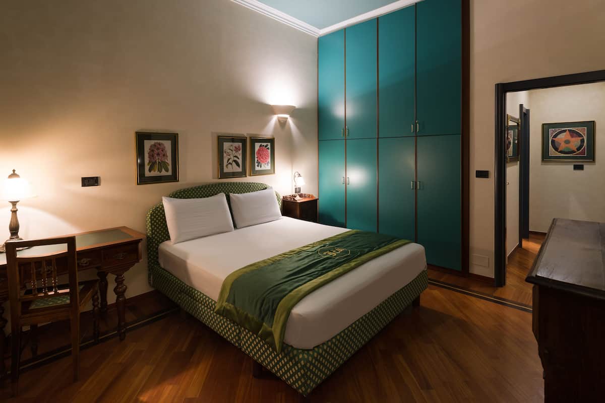 Quarto bem arrumado com cama, escrivaninha e guarda-roupa.