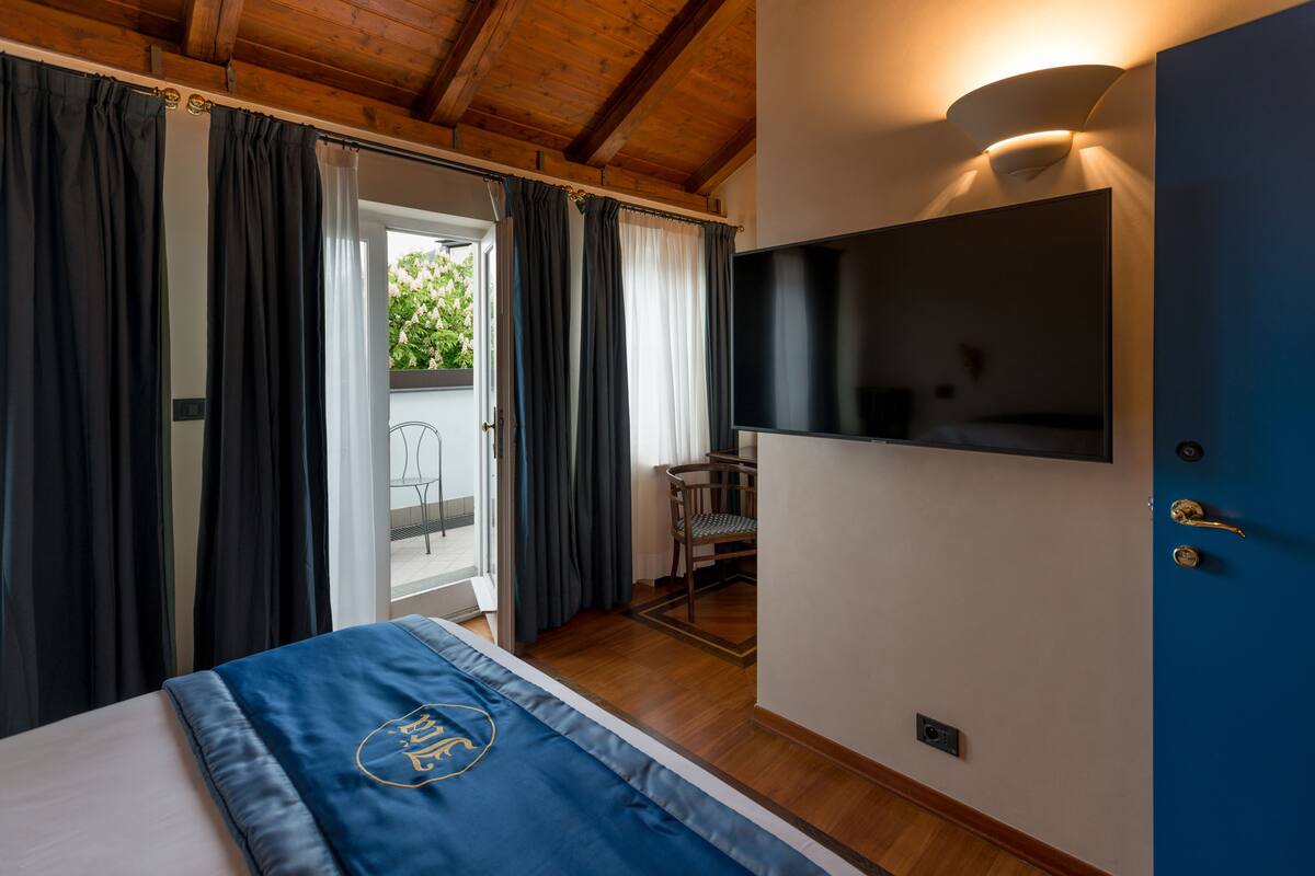Quarto com cama, televisão na parede e uma porta.