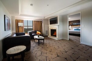 Quarto de hotel com lareira, televisão, sofá e vista para o exterior.