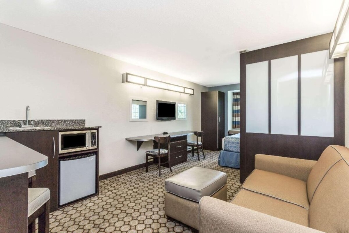 Quarto de hotel compacto com cozinha compacta, cama, escrivaninha e televisão.
