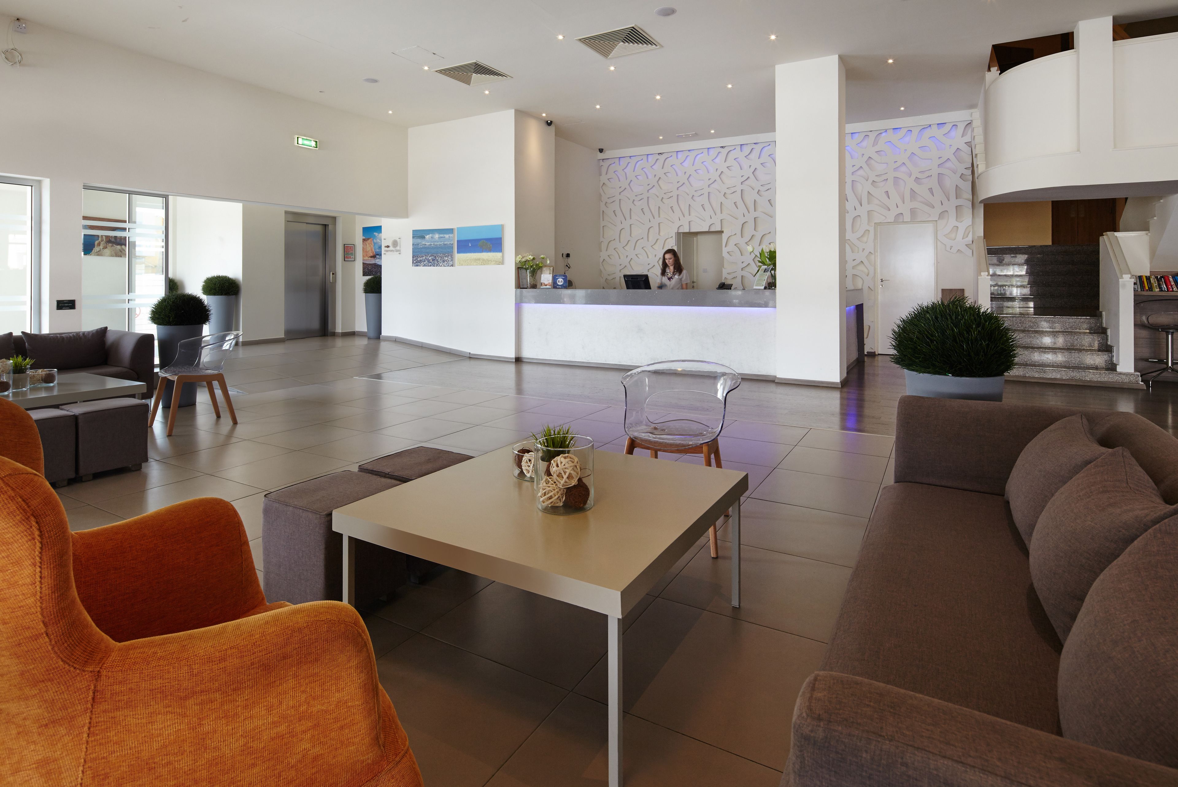 Um lobby de hotel moderno com balcão de recepção, área de estar e escada.