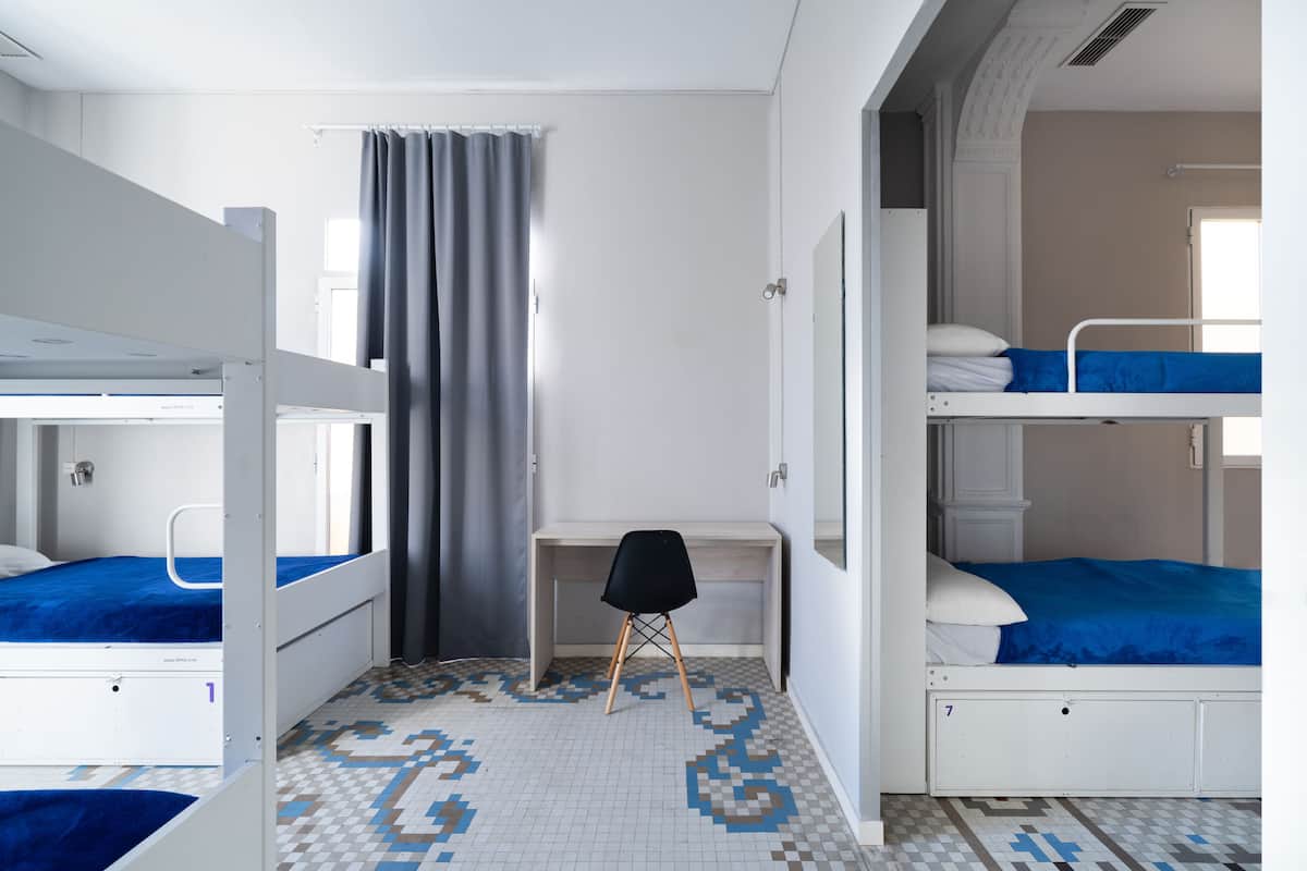 Quarto com beliches, uma escrivaninha e uma cadeira.