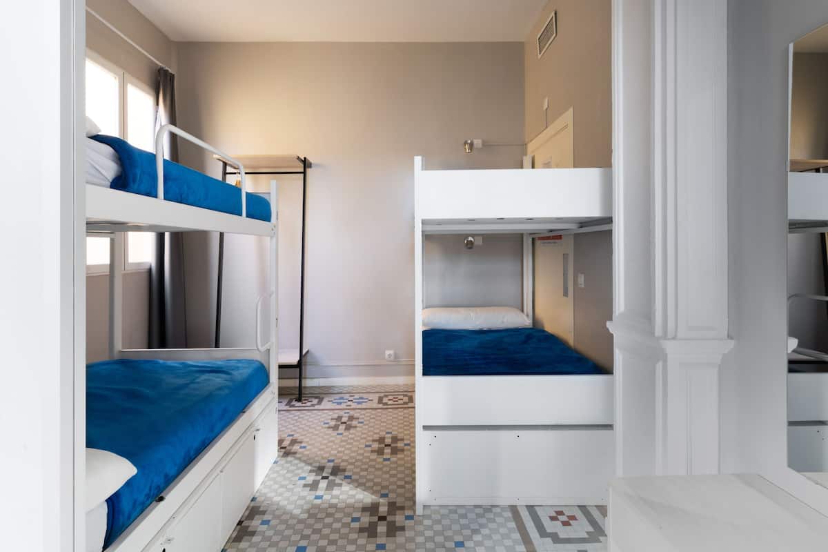 Quarto com beliches, piso estampado e janela com cortinas.