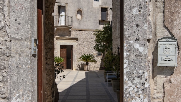 Entrada de um edifício com arco de pedra e uma placa com a inscrição 'Il Carmine'.