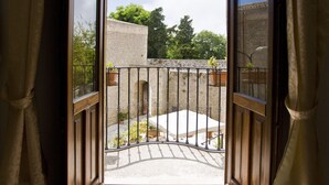 Uma porta aberta que dá para uma varanda com vista para um jardim e um edifício.