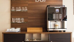 Uma área de bar com máquina de café, copos e balcão de madeira.