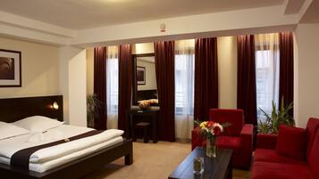 Quarto de hotel com cama, escrivaninha, sofá vermelho e mesa de centro.