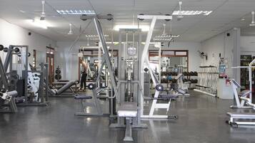 Uma academia com diversos equipamentos de exercício, incluindo aparelhos de musculação e pesos livres.