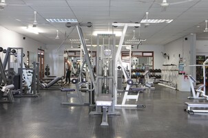 Uma academia com diversos equipamentos de exercício, incluindo aparelhos de musculação e pesos livres.