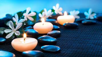 Primeiro plano de velas e pedras lisas sobre uma superfície texturizada.