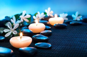 Primeiro plano de velas e pedras lisas sobre uma superfície texturizada.