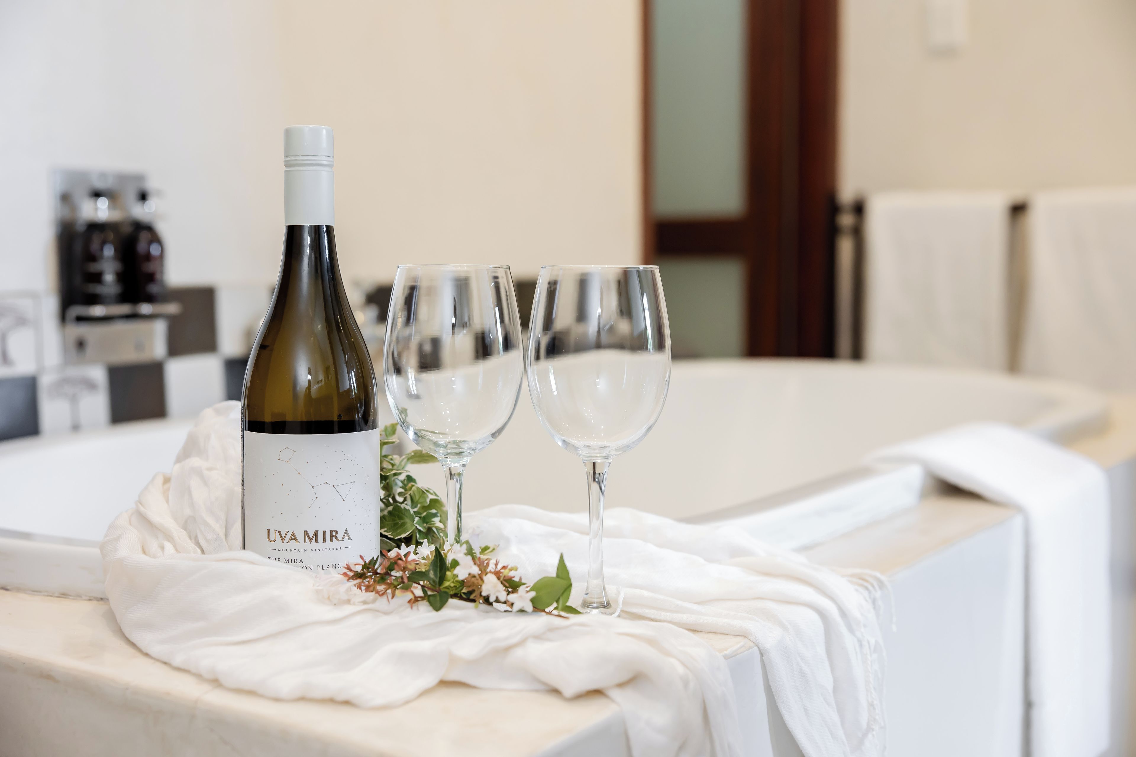 Uma garrafa de vinho Uvamira, dois copos e um pano branco sobre uma mesa.