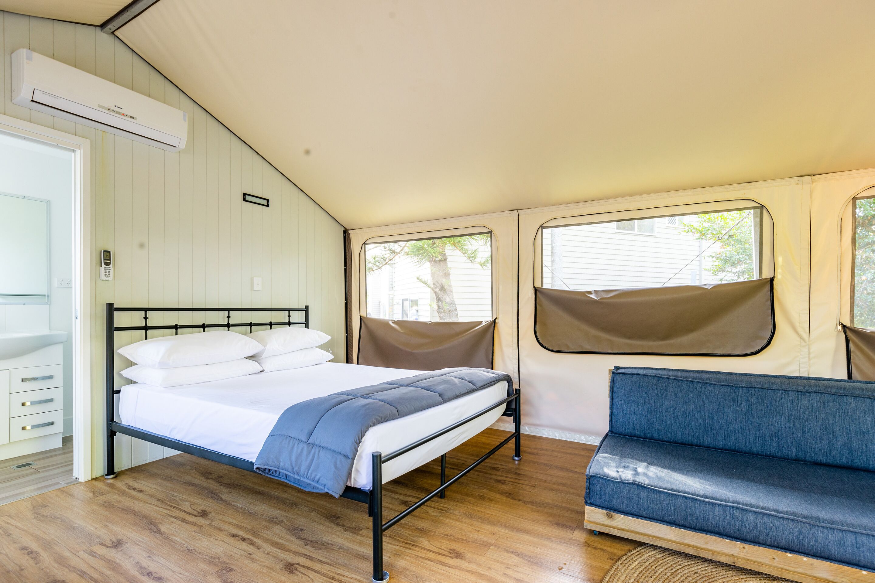 Quarto com cama, sofá, janela e aparelho de ar condicionado.