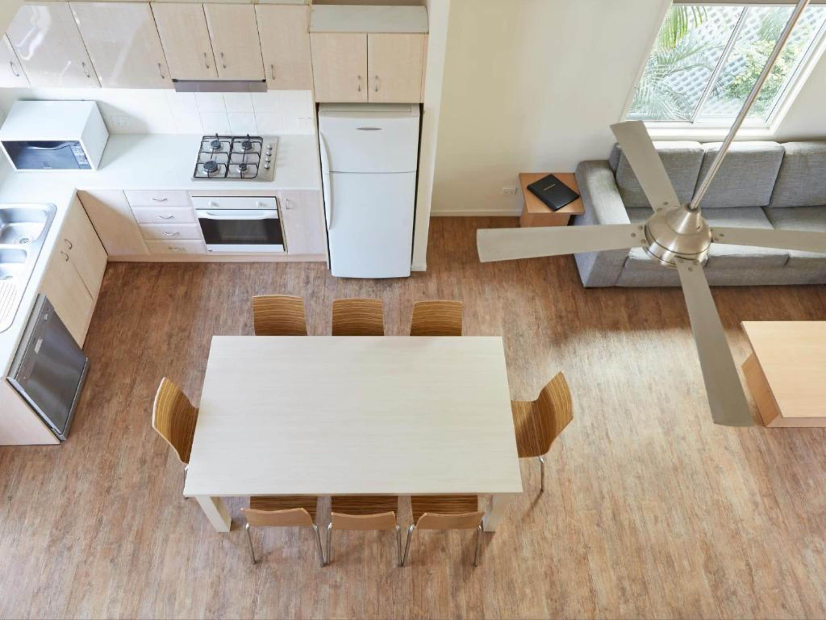 Uma cozinha moderna com área de refeições, um sofá e um ventilador de teto.