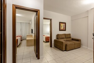 Quarto de hotel com cama grande, sofá, televisão e um quadro na parede.