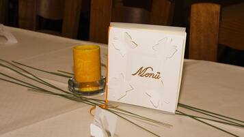 Uma mesa com um cardápio, uma vela e alguns elementos verdes.