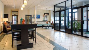 Um hall amplo com bar central, áreas de estar e grandes janelas com vista para o exterior.