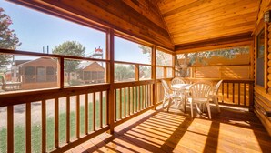 Um deck de madeira com guarda-corpo, uma mesa e cadeiras.