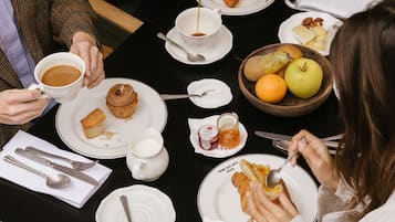 Uma mesa de jantar com pratos de comida, xícaras e uma tigela de frutas.