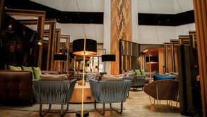 Um interior moderno com área de estar central, pé direito alto e mobiliário contemporâneo.
