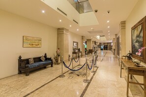 Um hall de hotel com piso de mármore, um sofá, uma pintura e uma estátua.