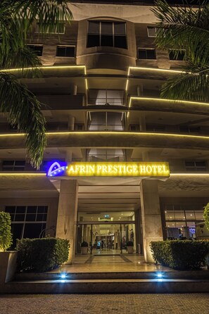 Exterior do Hotel Afrin Prestige, com uma placa iluminada de destaque, vários andares e uma entrada bem iluminada.