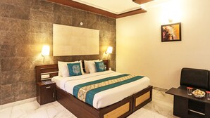 Quarto de hotel com uma cama grande, duas mesas de cabeceira, uma TV de tela plana e um quadro na parede.