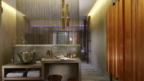 Um spa moderno com área de estar, uma grande bacia de metal e uma pequena mesa com toalhas e objetos decorativos.